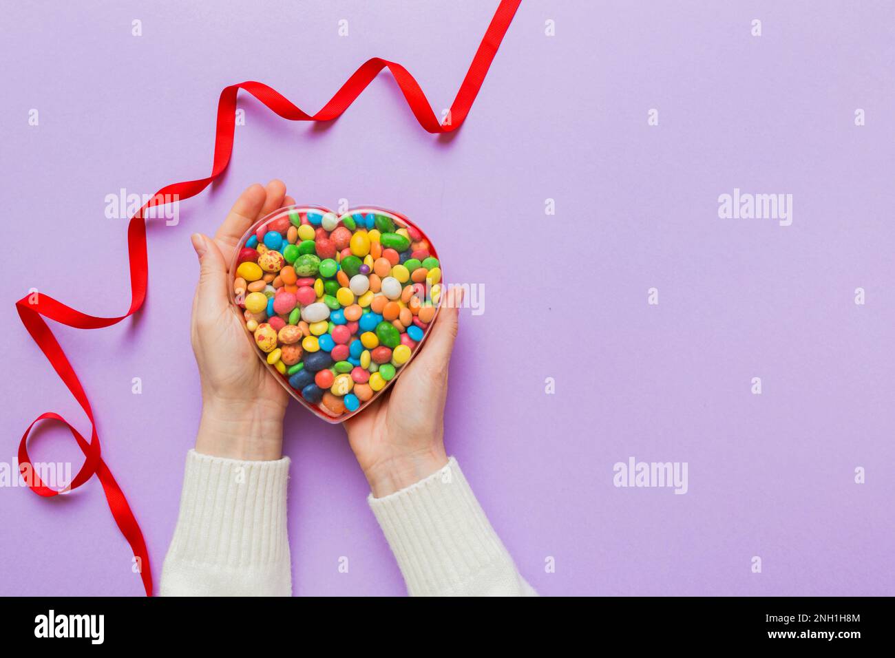 Female hands with delicious candies in box on color background Stock ...