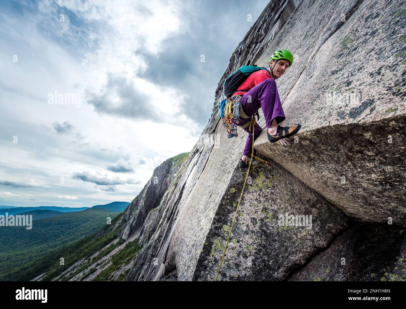 Man with tattoos climbing steep rock wall face Stock Photo - Alamy
