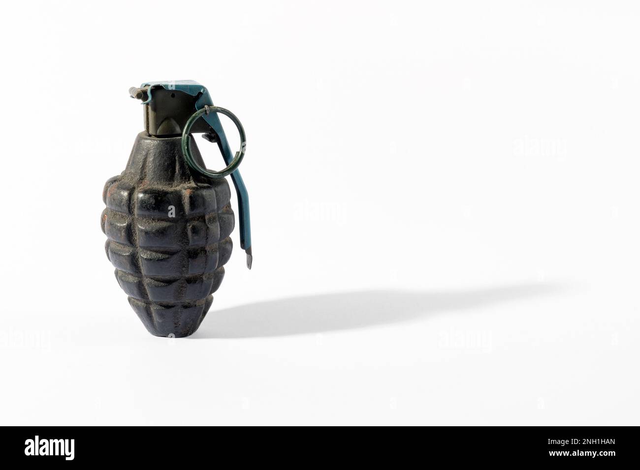 Aged hand grenade with shell covered with dust casting shadow on white ...