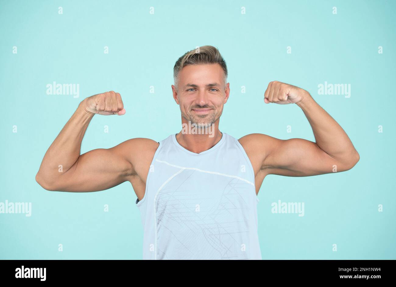 Happy muscular man blue background. Sportsman muscular arms showing ...