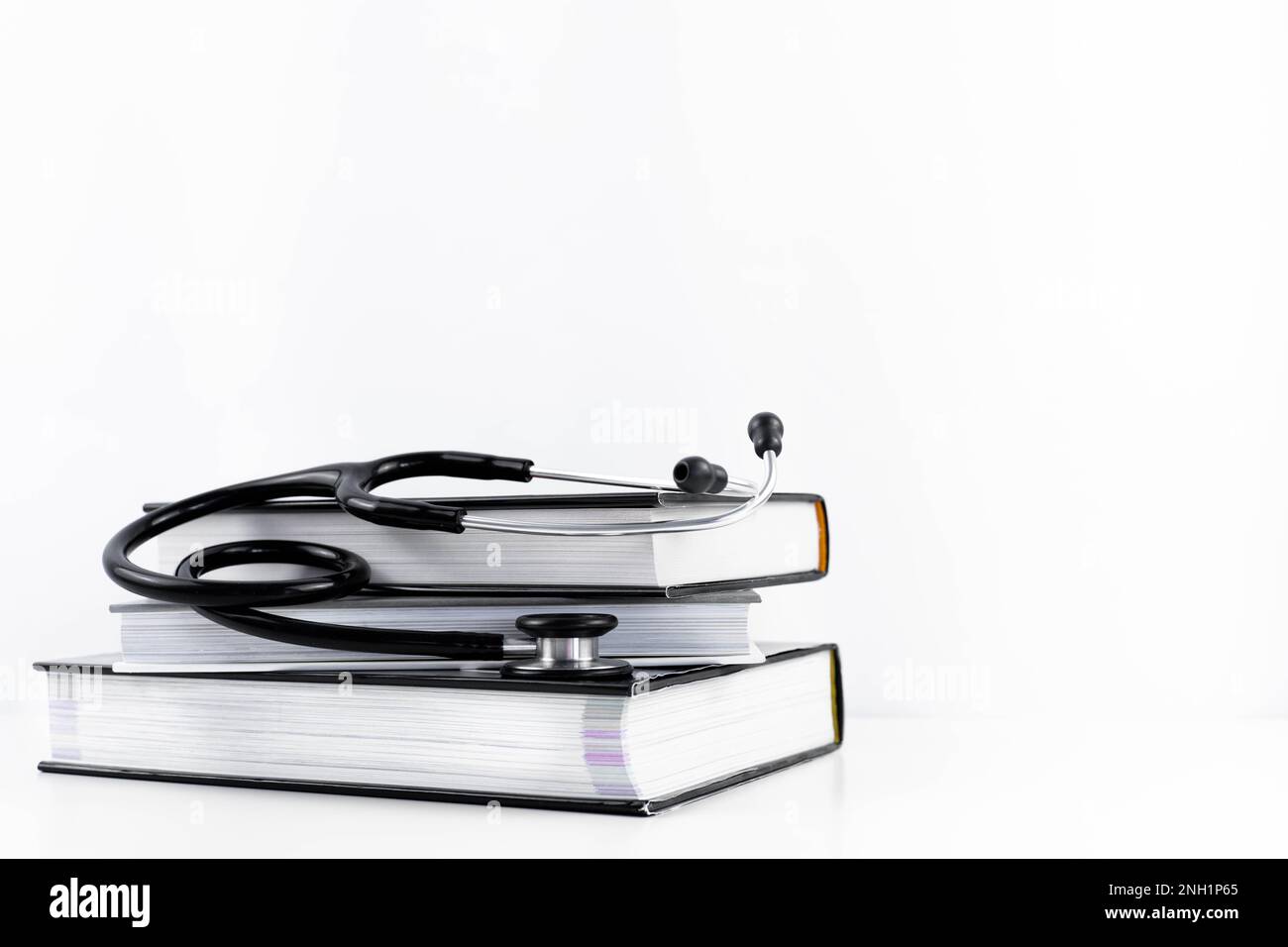Stethoscope listening to stacked medicine books. White background with ...