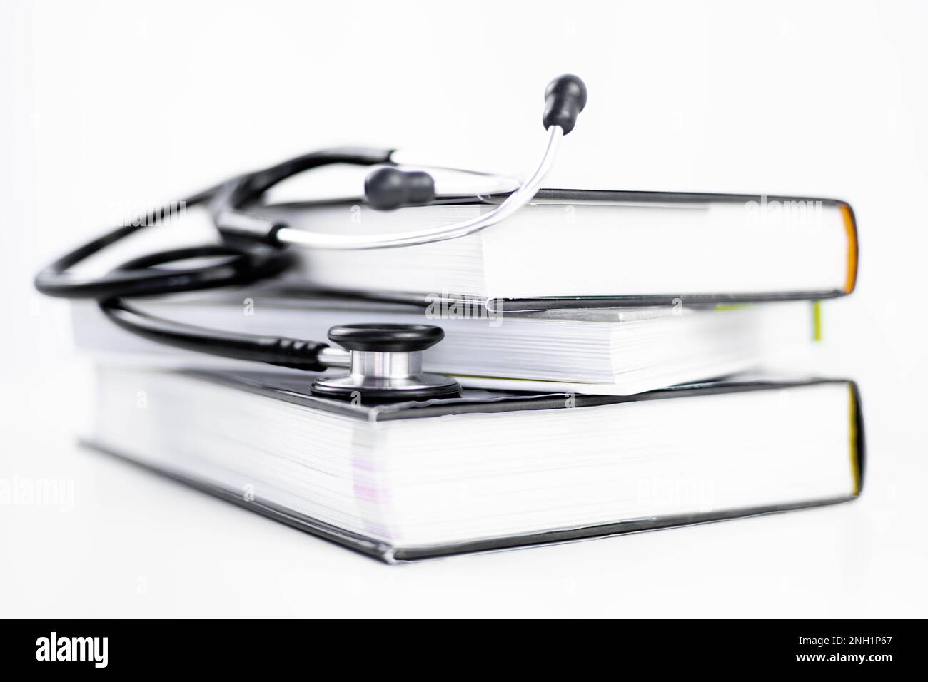 Stethoscope listening to stacked medicine books. White background with ...