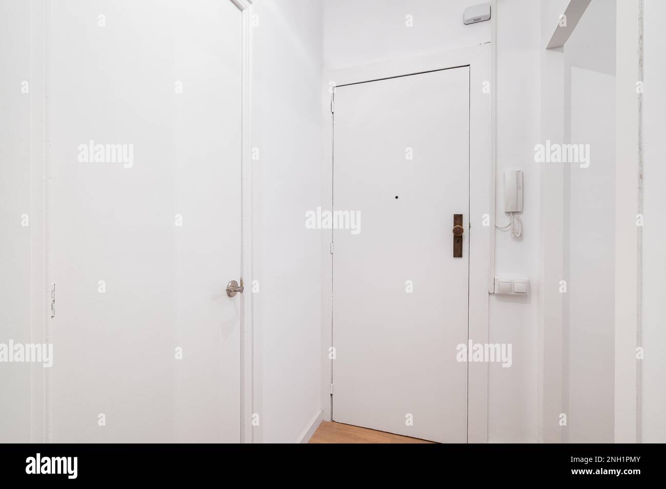 White front door to apartment with intercom on wall. There is peephole ...