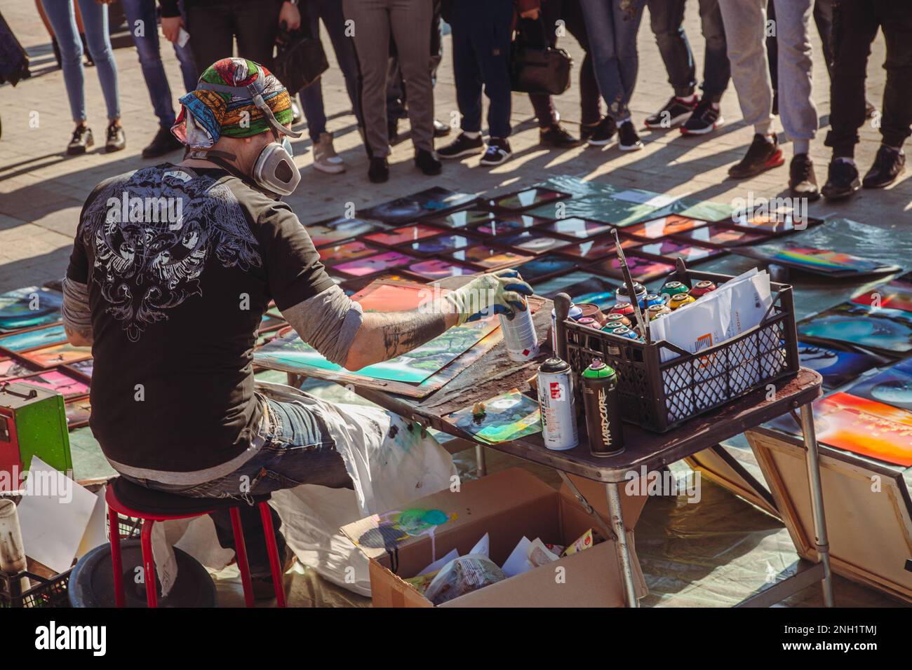 Artist on embankment, surrounded by crowd of people, draws in technique ...