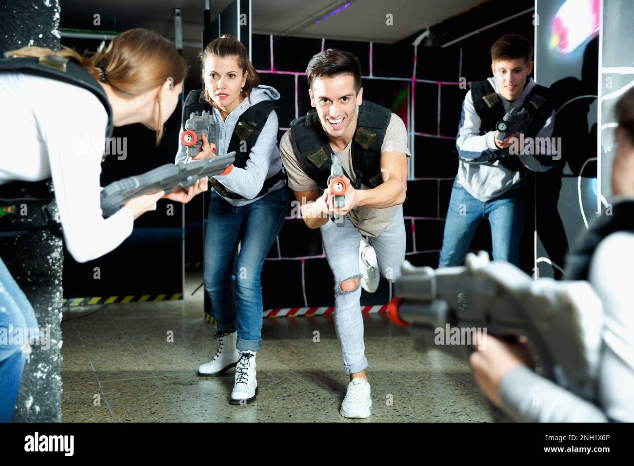 Cheerful Laser tag players young mens and womens playing in teams in ...