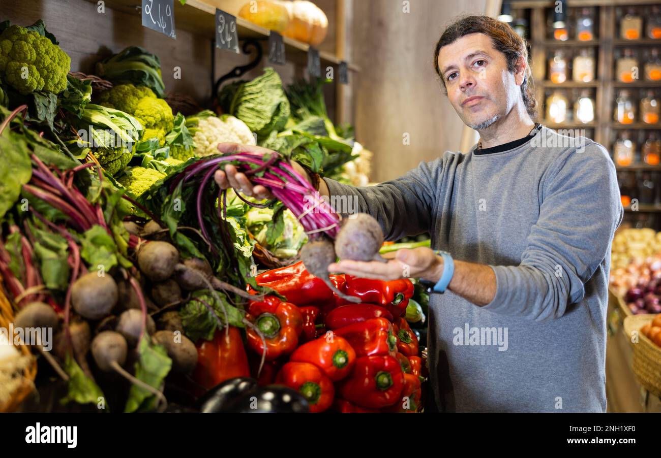 Man diligently picking out beets to buy in vegetable aisle of ...