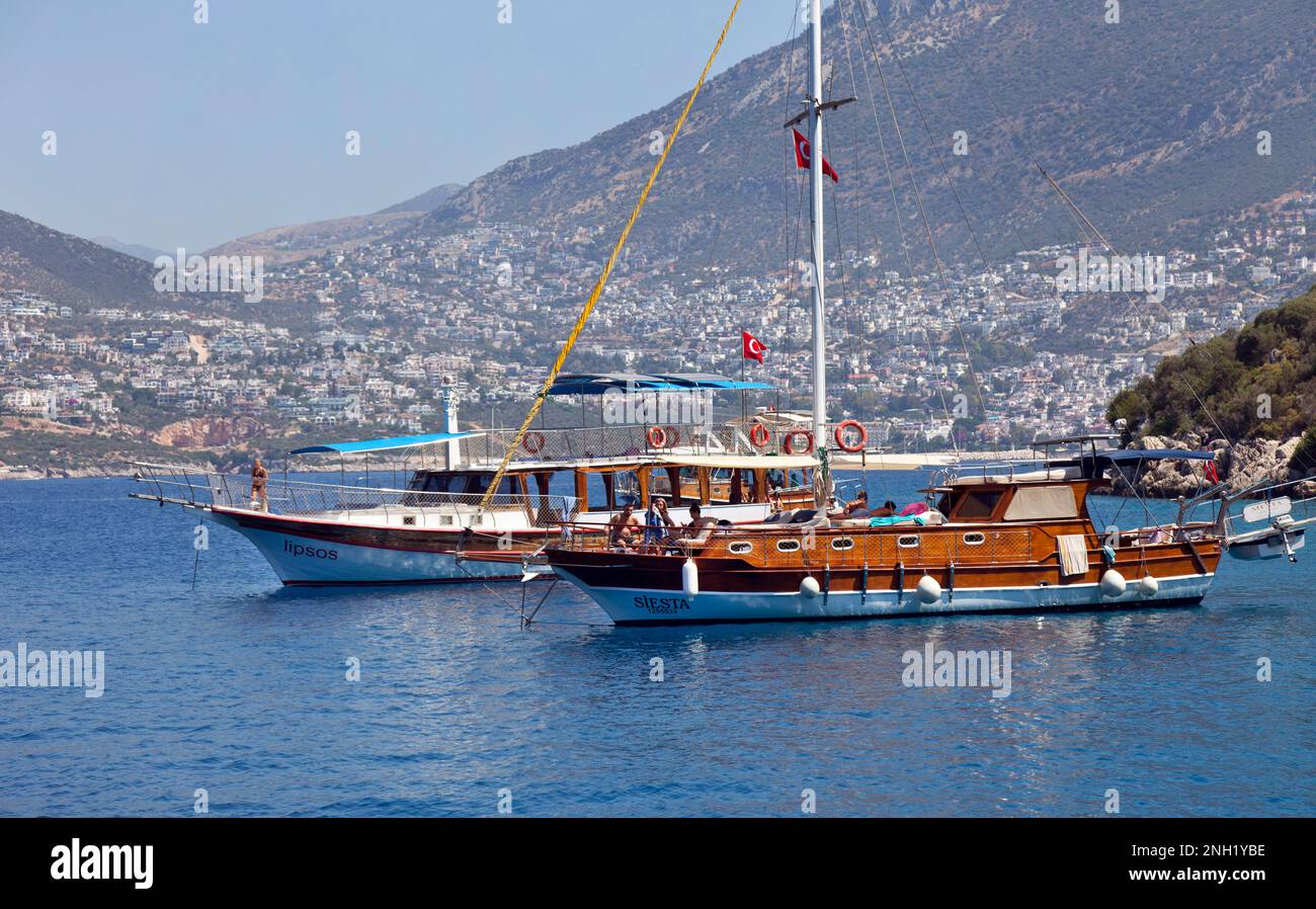 Boats ( gulets ) moored in the bay of Kalkan with the village of Kalkan ...