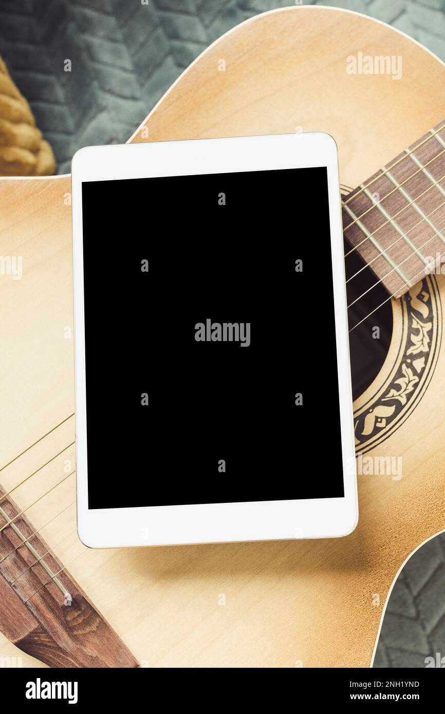 Acoustic guitar and digital tablet on couch at cozy home background ...