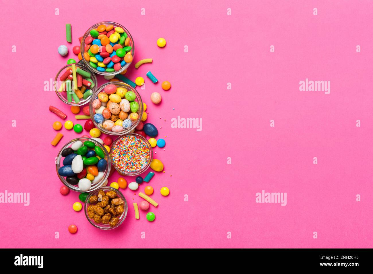 different colored round candy in bowl and jars. Top view of large ...