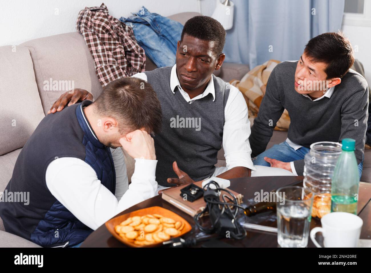 Friends calming distressed guy Stock Photo - Alamy