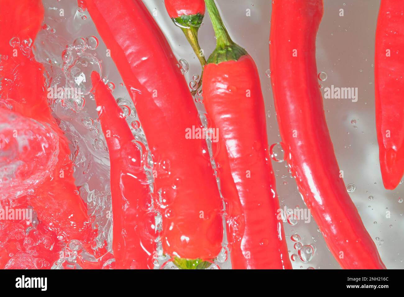Red chilli peppers close-up in liquid with bubbles. Red chilli peppers ...