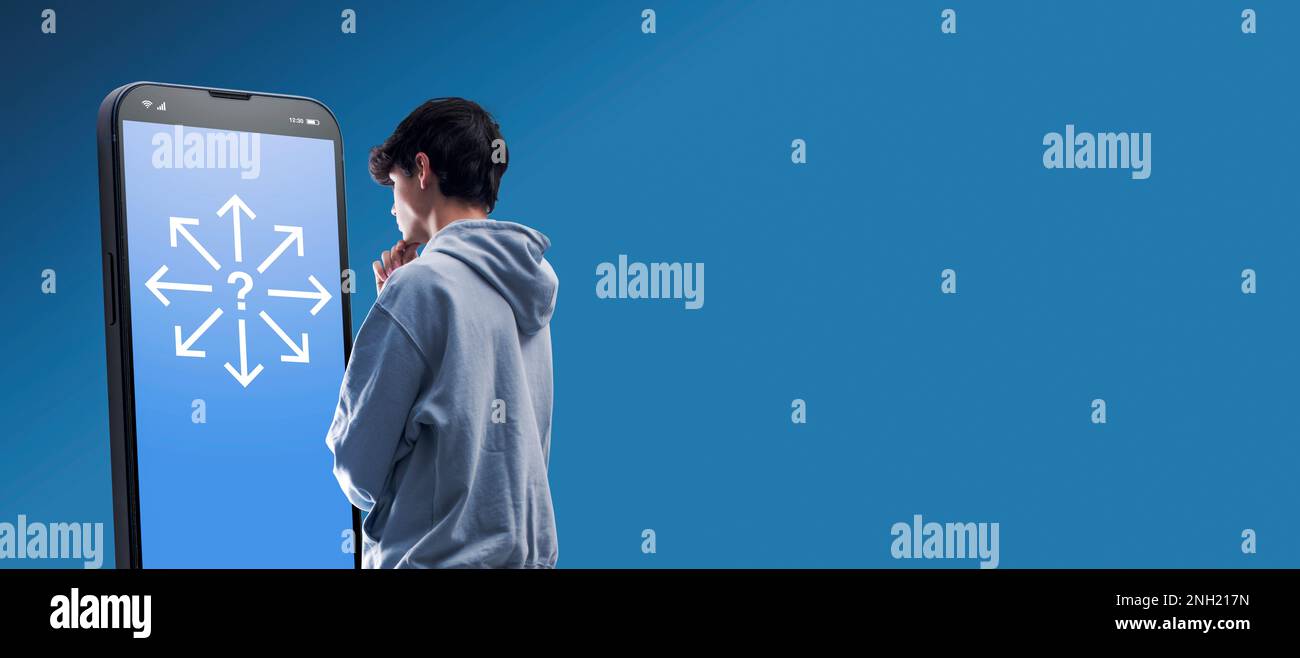 Pensive teenager looking at a big smartphone and taking a decision ...