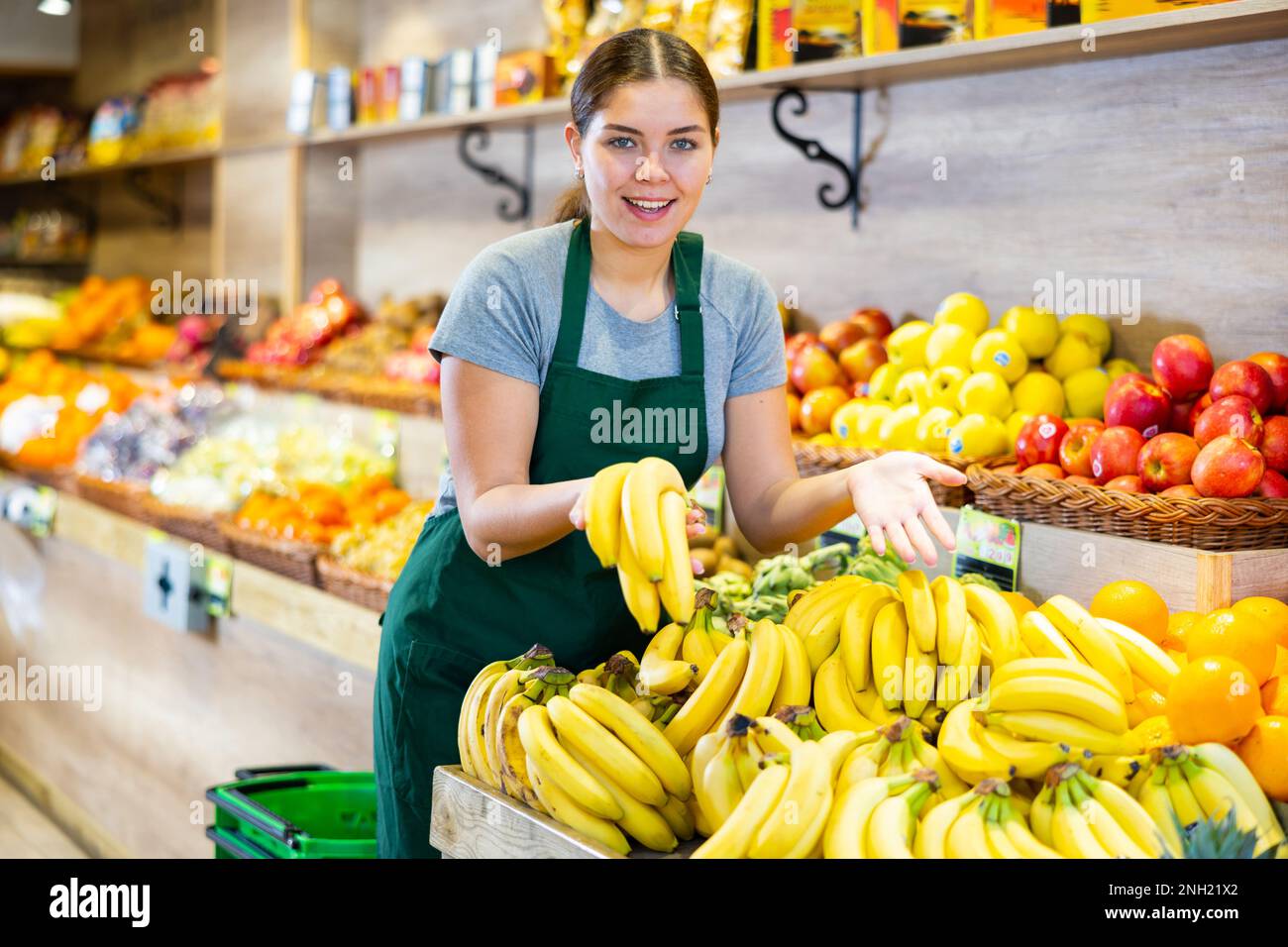 Positive female seller with ripe bananas on supermarket Stock Photo - Alamy