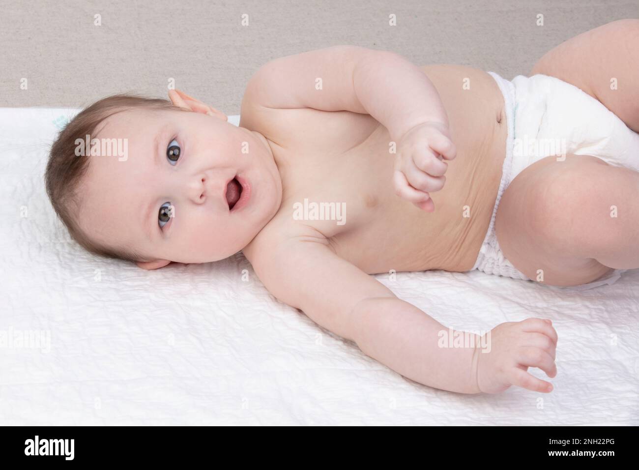 A six-month-old baby boy in a diaper lies on a diaper. The concept of ...
