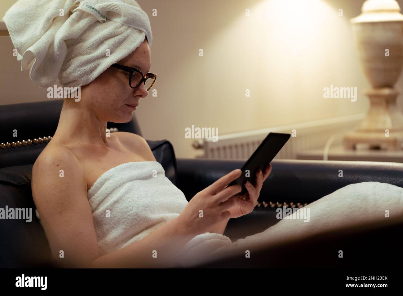 Young girl with eyeglasses reading relaxed after showering, beauty ...