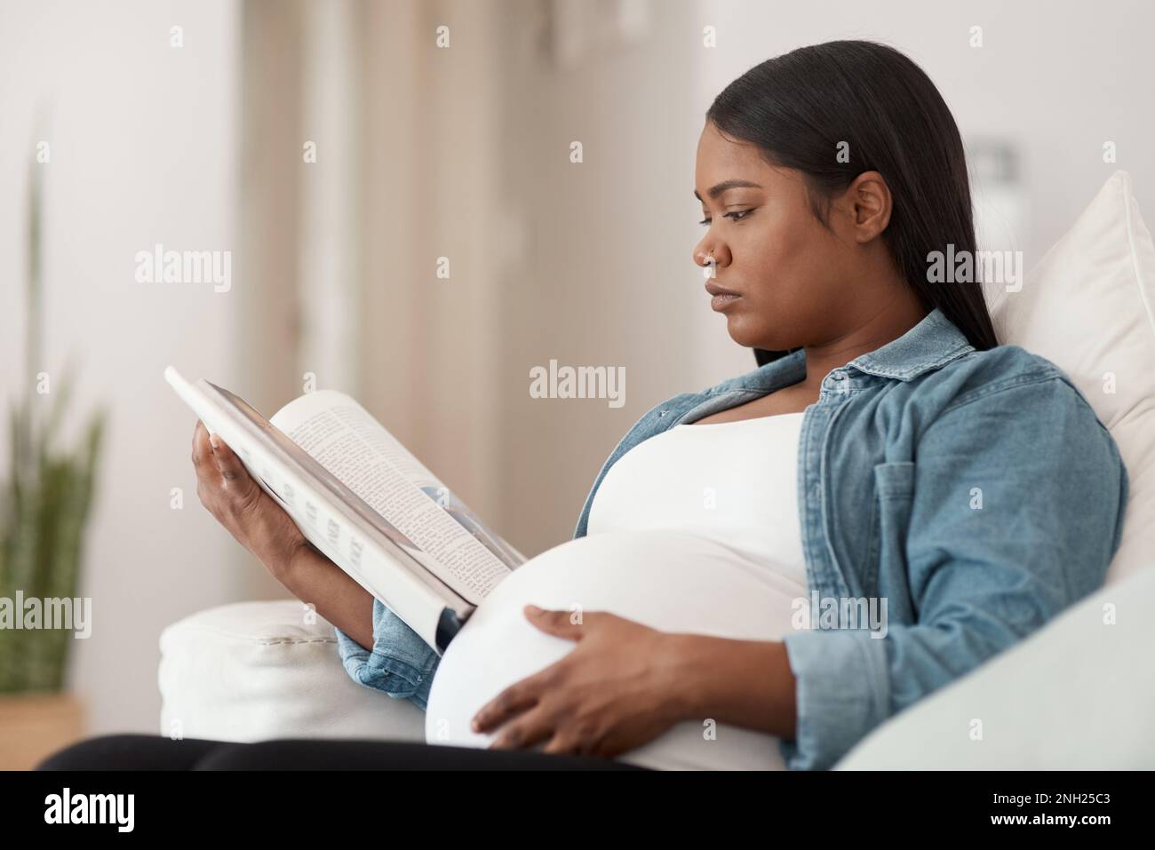 Paging through another pregnancy book. a pregnant woman reading a book ...