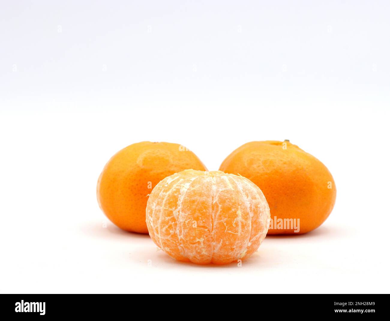A closeup of three mandarin fruits white surface isolated white ...