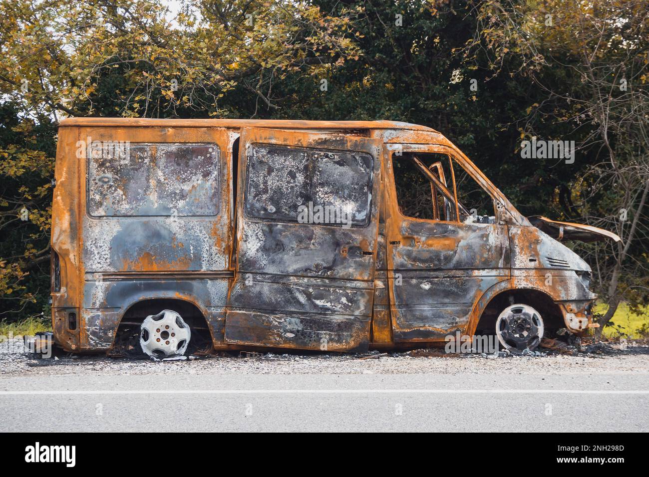 Burnt out big van next to the road. The car after the accident. A burnt ...