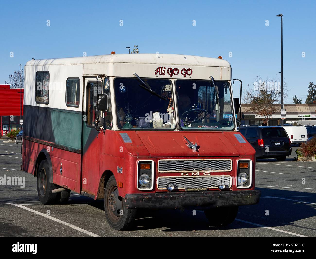 A vintage, rusty, red, white and green van which is being lived in ...