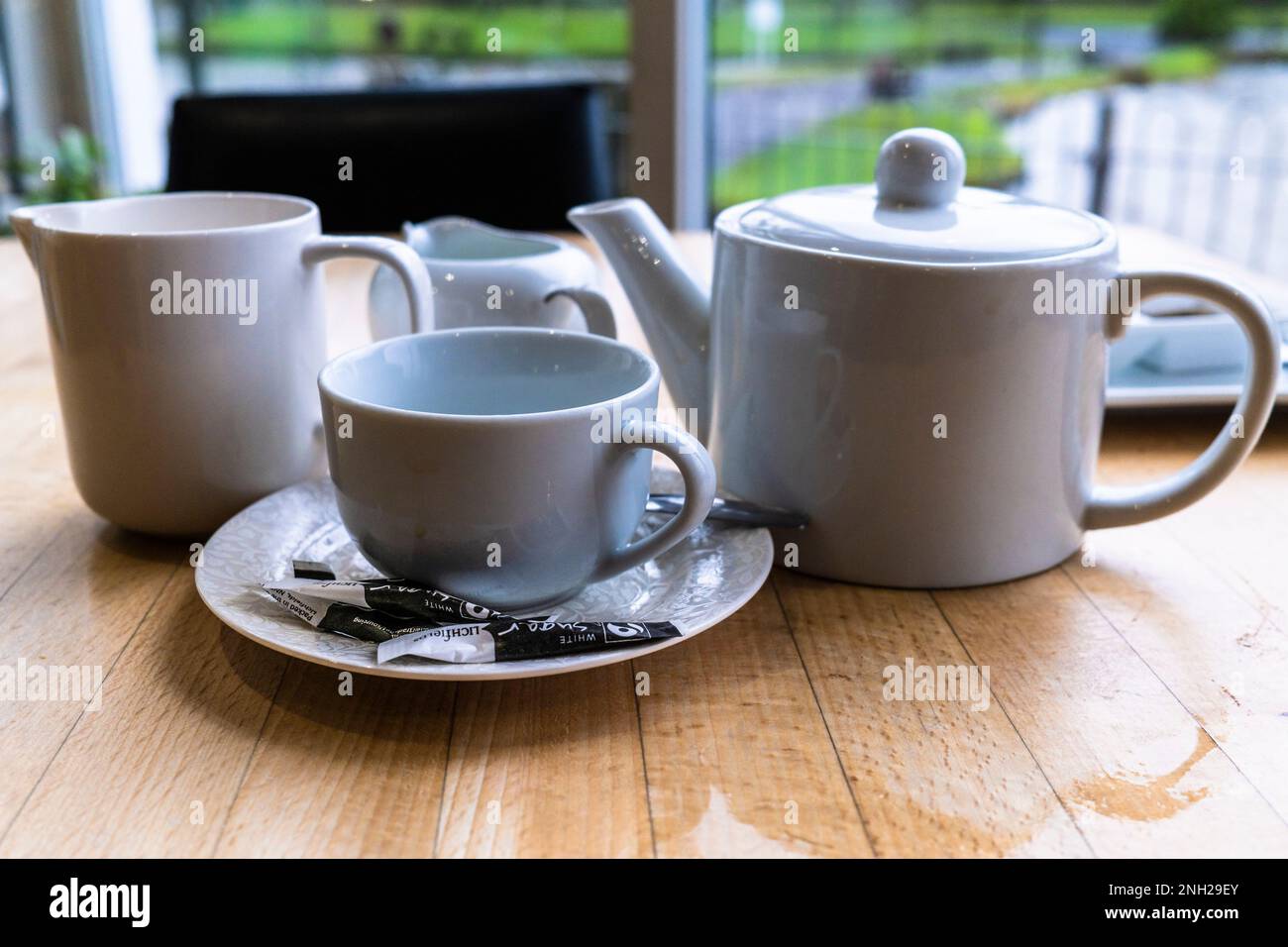 Milk jug, Tea cup and Saucer and a tea pot on a table in a restaurant ...