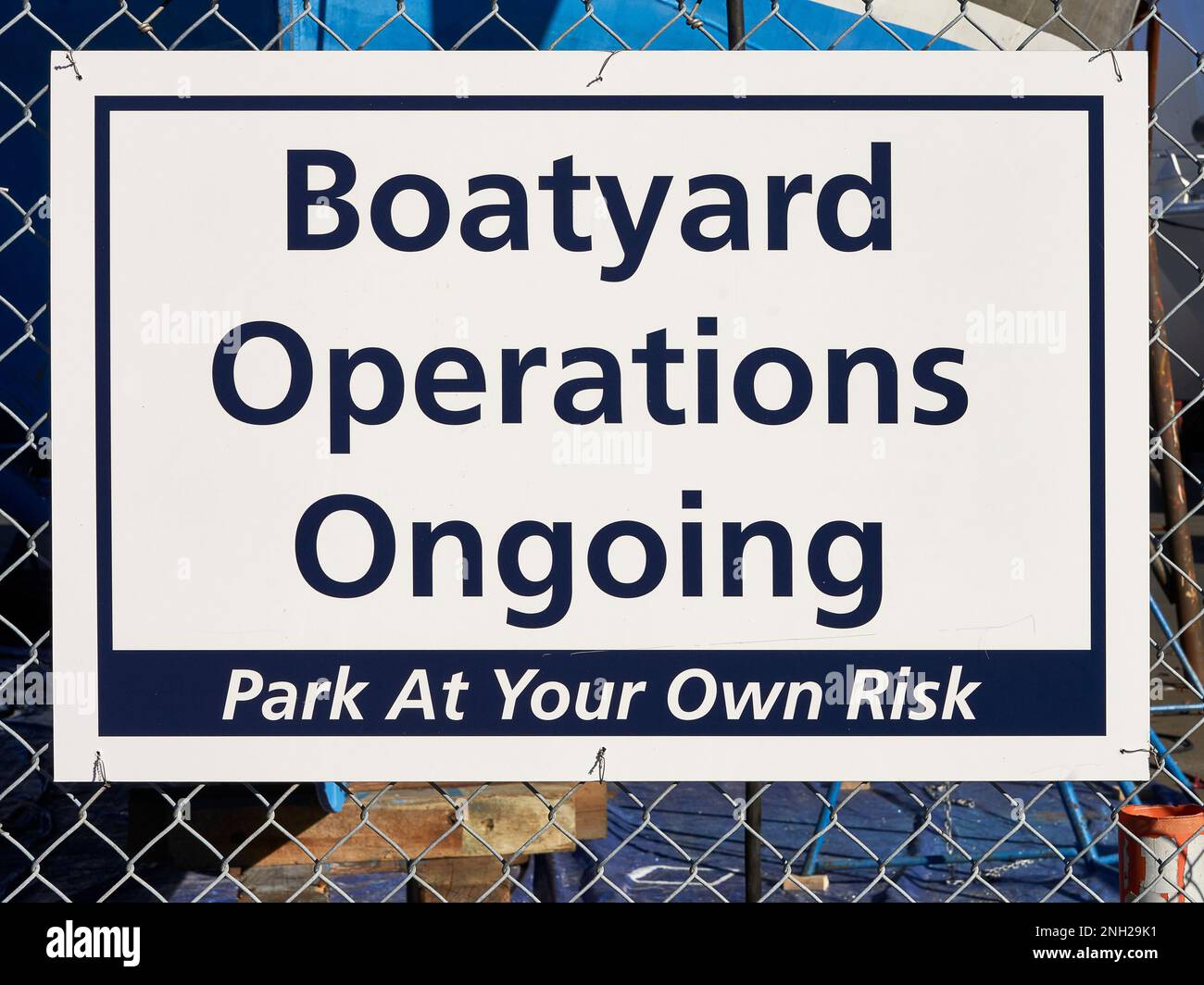 A warning sign on the wire fence of a maintenance boatyard informing ...
