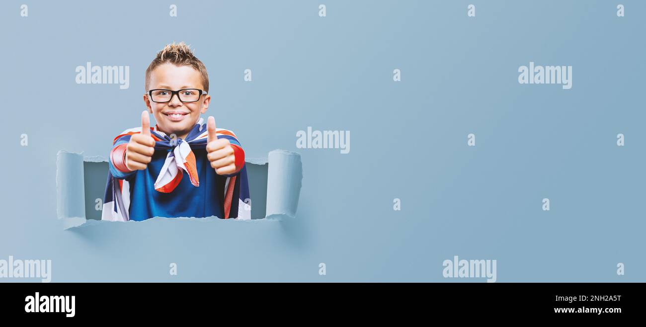 Smiling cute superhero thumbs up, he is wearing a British flag as a ...