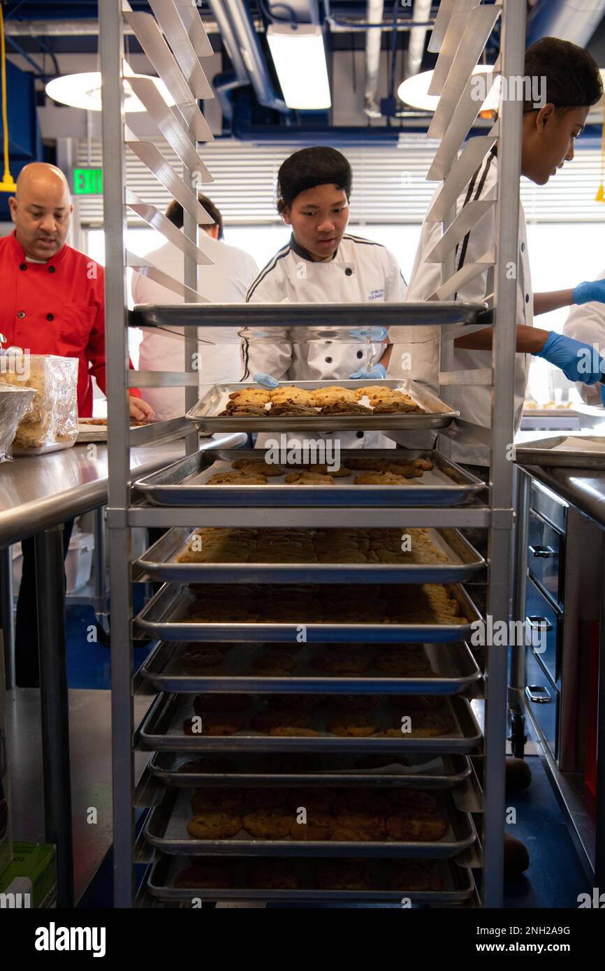 A Yokota High School Student pulled a tray of cooled cookies to package ...