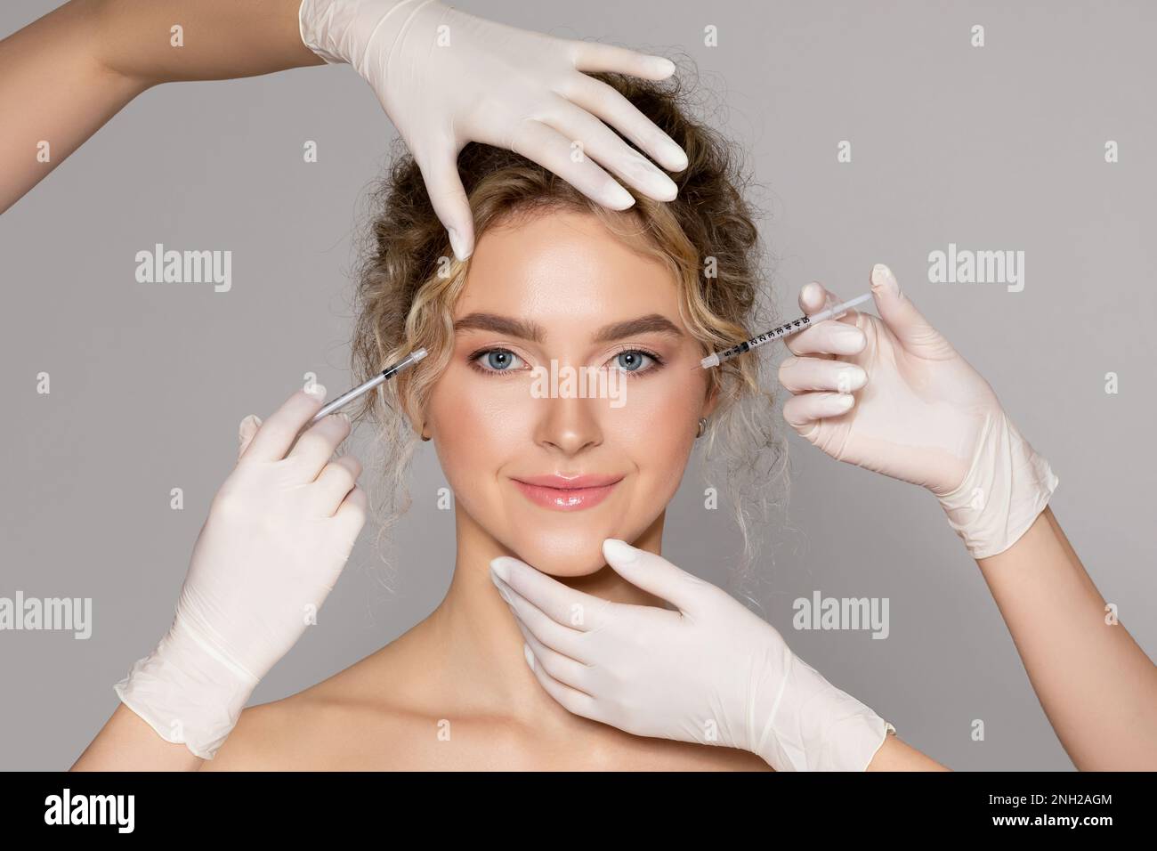 Attractive young woman getting injection for eyes area by two ...