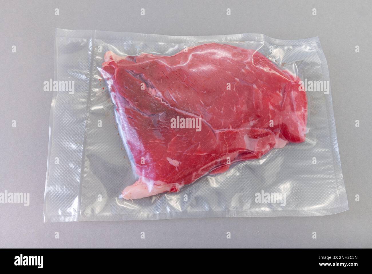 Raw beef steak in vacuum-sealed package for sous vide cooking on gray ...