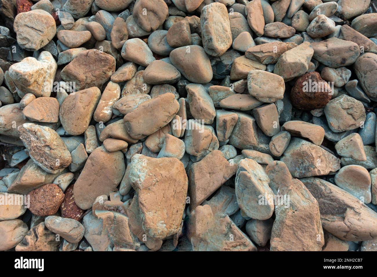 top down close-up view of naturally rounded beach rocks on the seashore ...