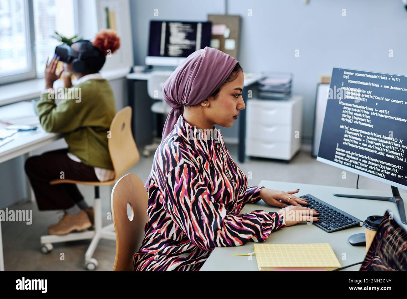 Side view portrait of Muslim young woman as software developer writing ...