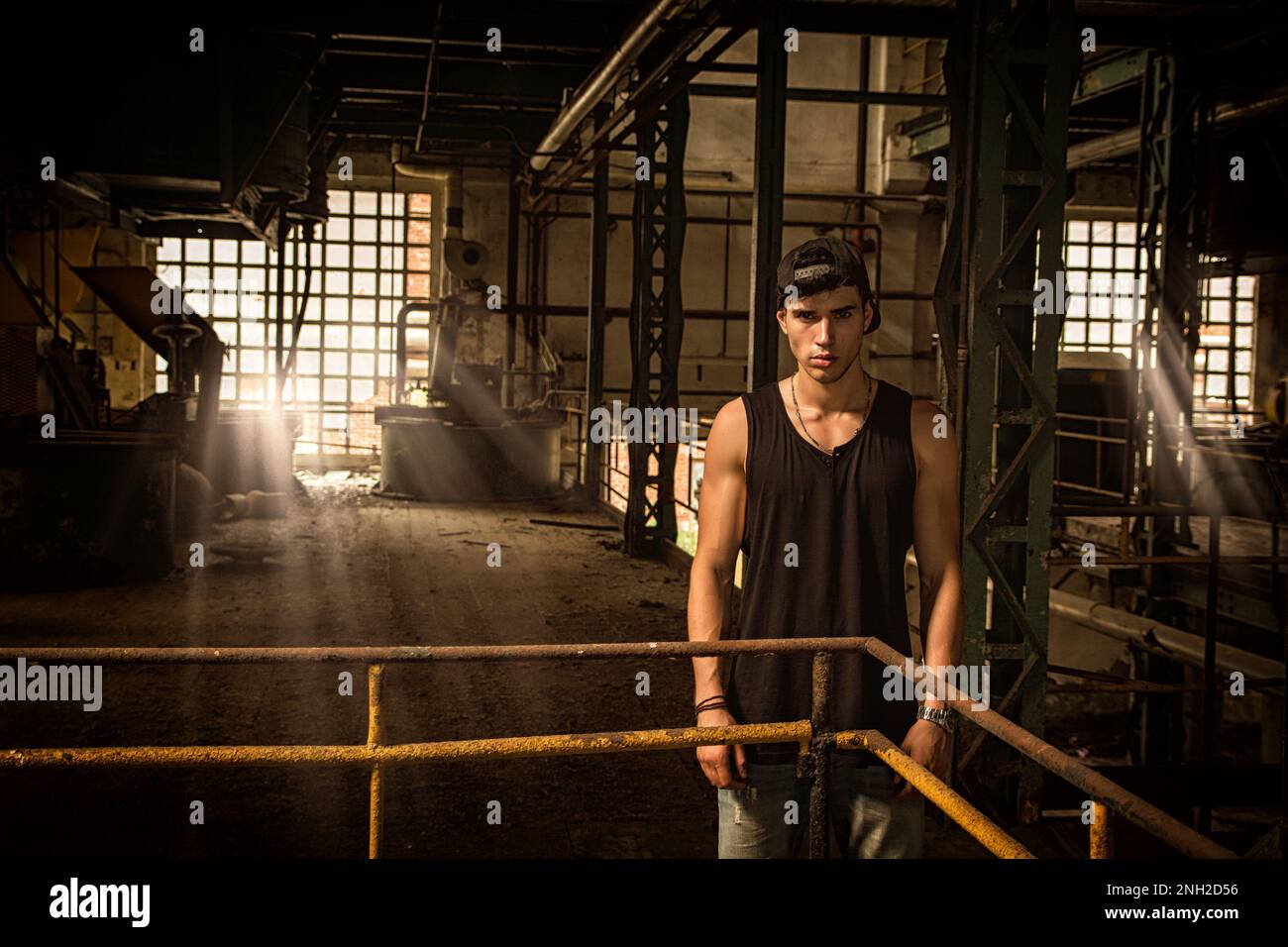 Young man standing in abandoned factory building Stock Photo - Alamy