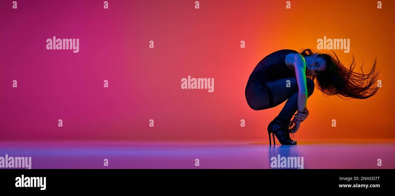 Young woman dancing high heel, stiletto dance over gradient pink orange ...