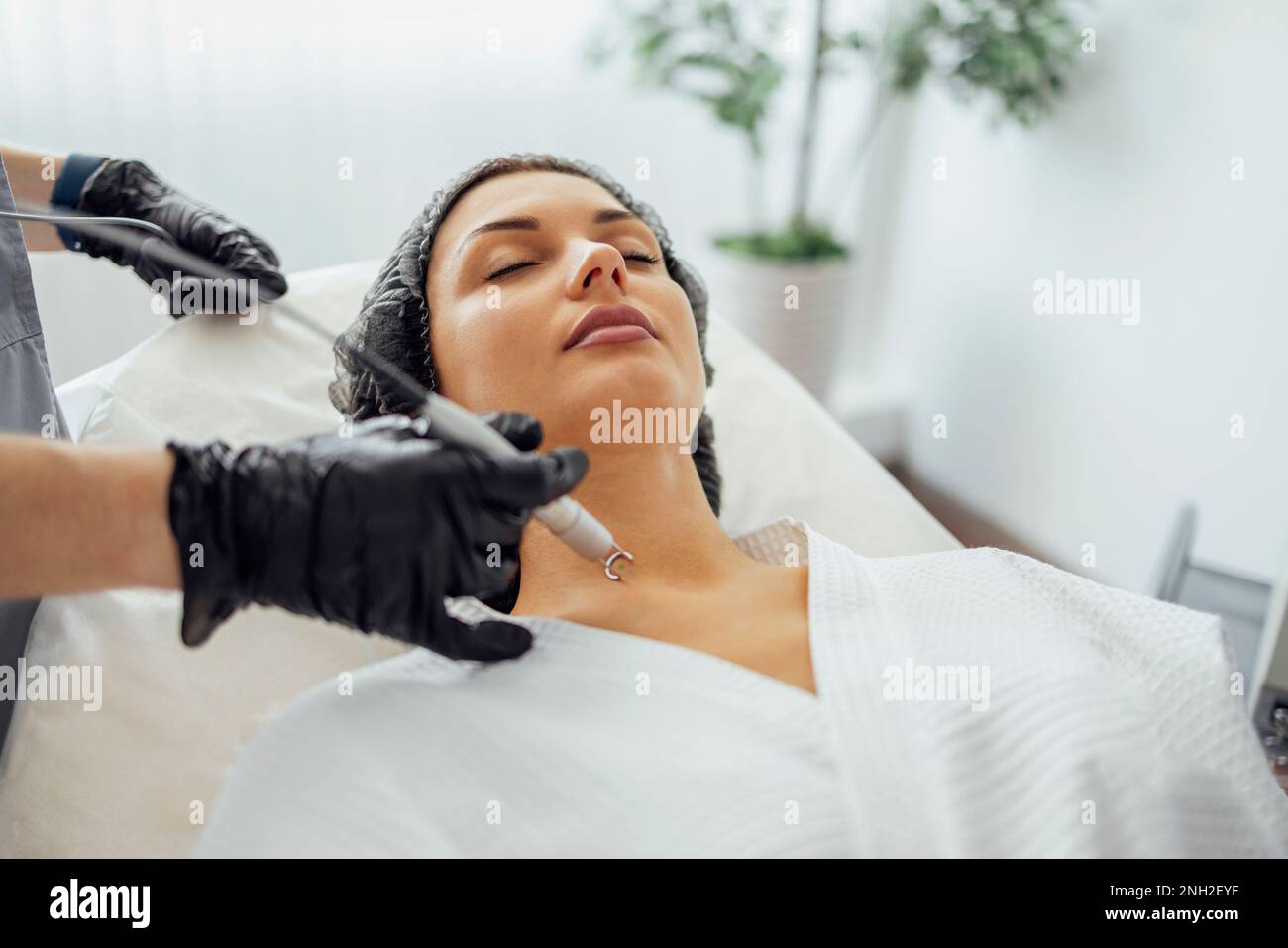 Beautiful caucasian young woman is doing a mole removal procedure in a ...