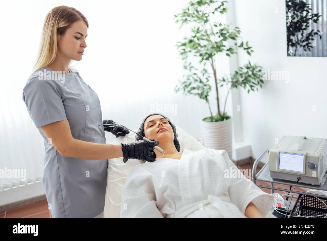 Beautiful caucasian young woman is doing a mole removal procedure in a ...