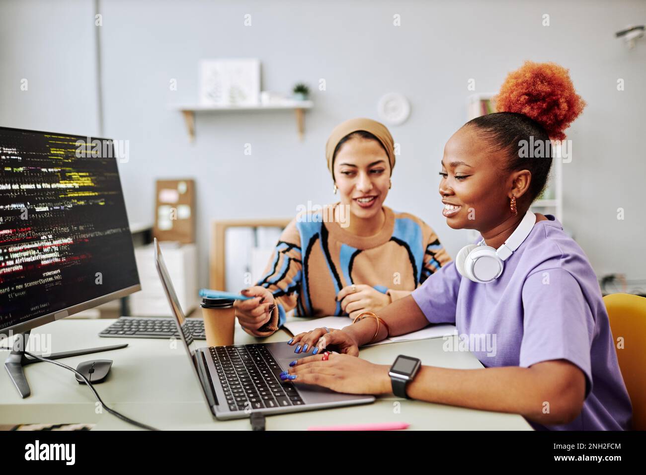 Side view portrait of two young women working on software development ...