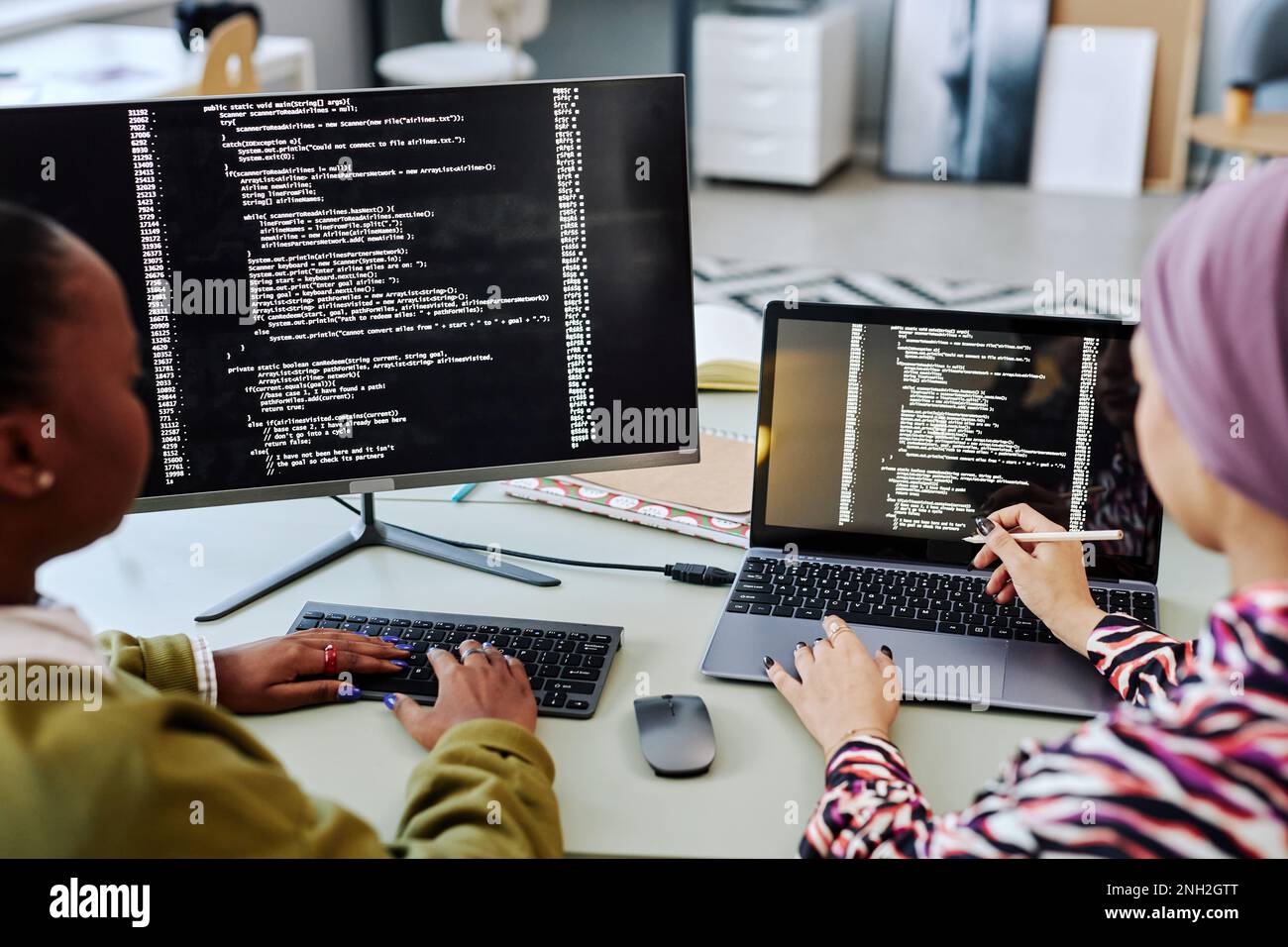High angle view at two people writing code and reviewing project ...