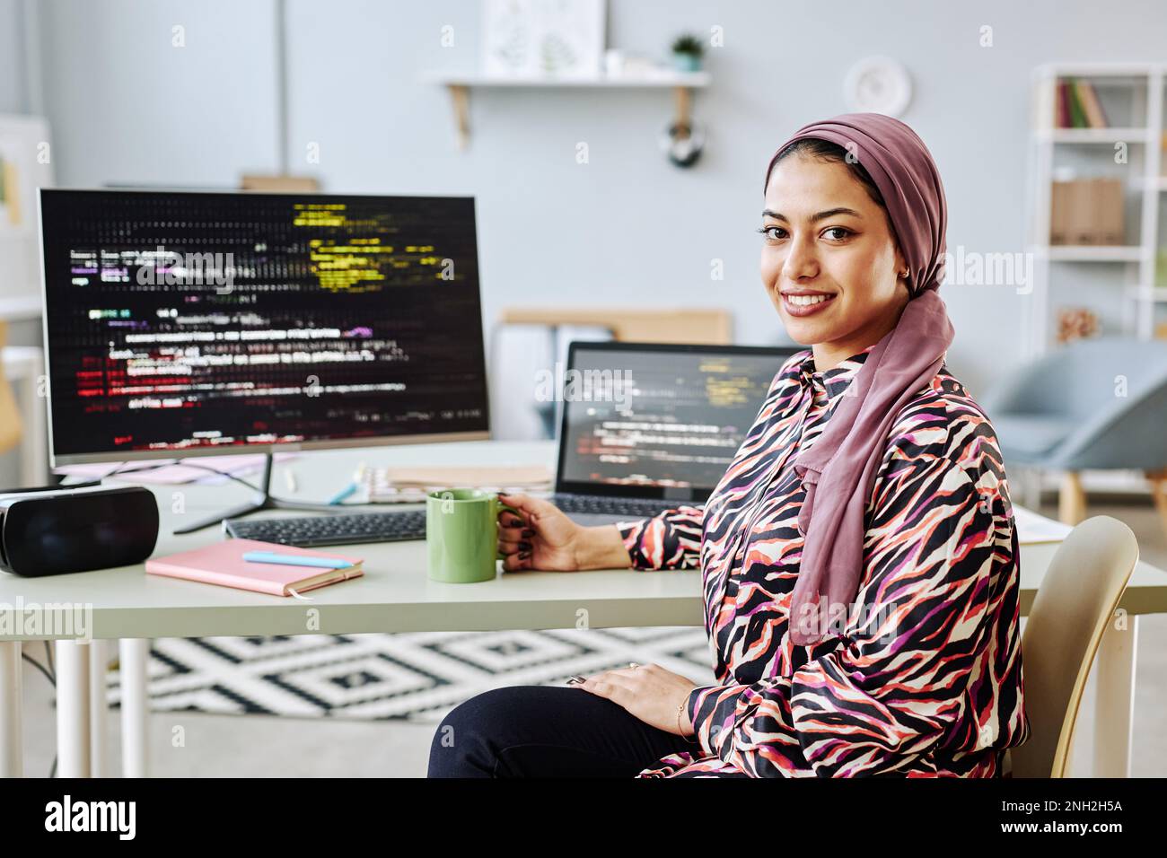 Portrait of Middle Eastern young woman working as software programmer and smiling at camera at ...