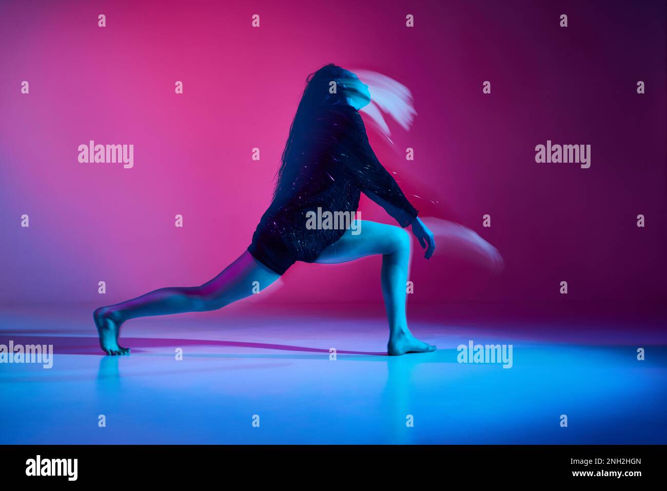 Young woman dancing contemp over gradient pink studio background in ...