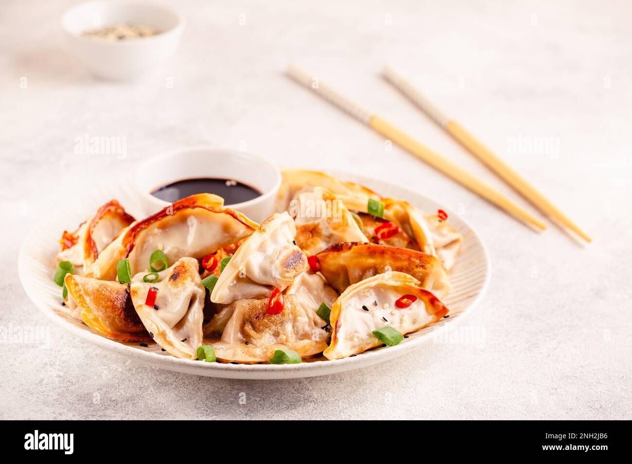 Fried dumplings served with green onions, sesame seeds and chili ...