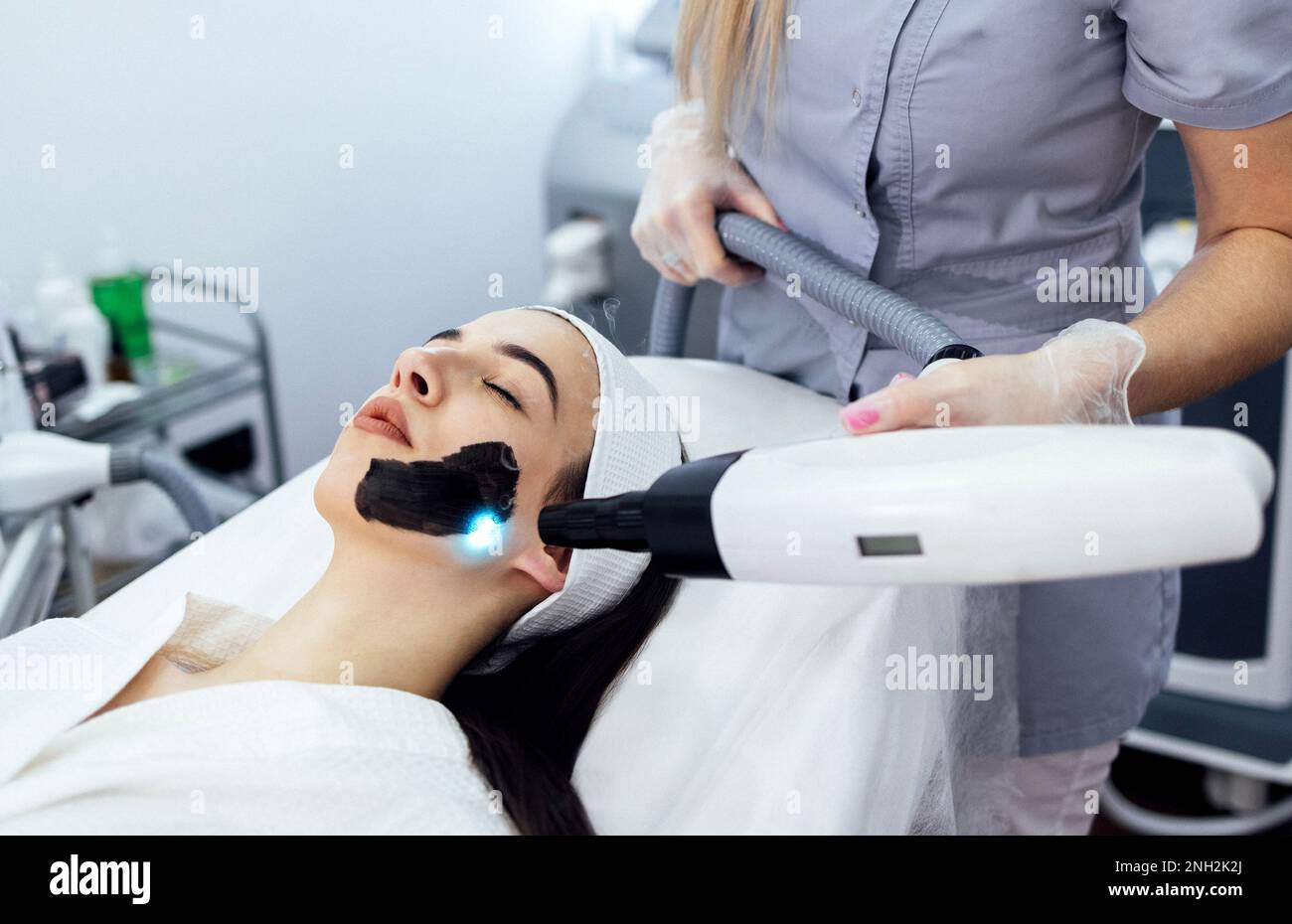 Beautician holding beauty laser near woman face covered with carbon ...