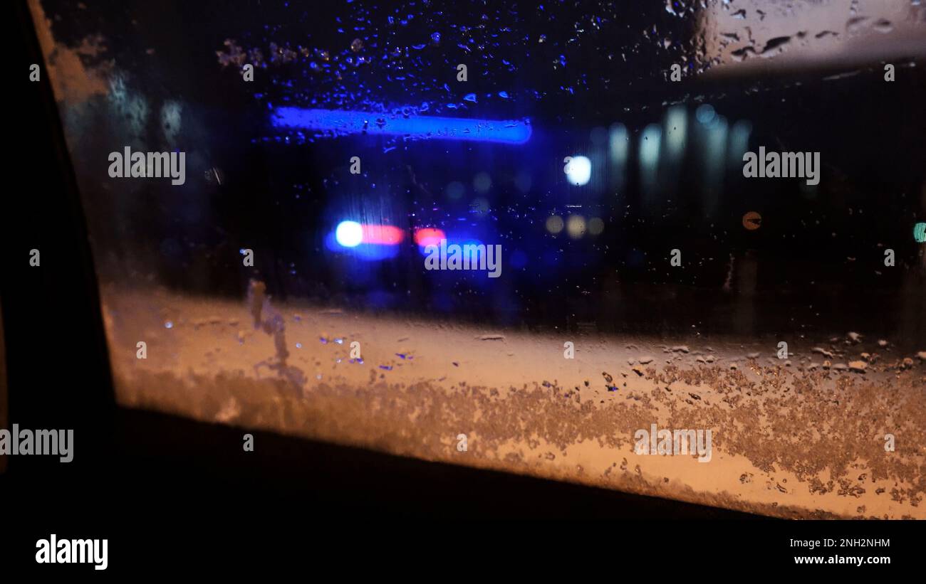 Misted car window. Melting snow on a car window. Car headlights, bokeh ...