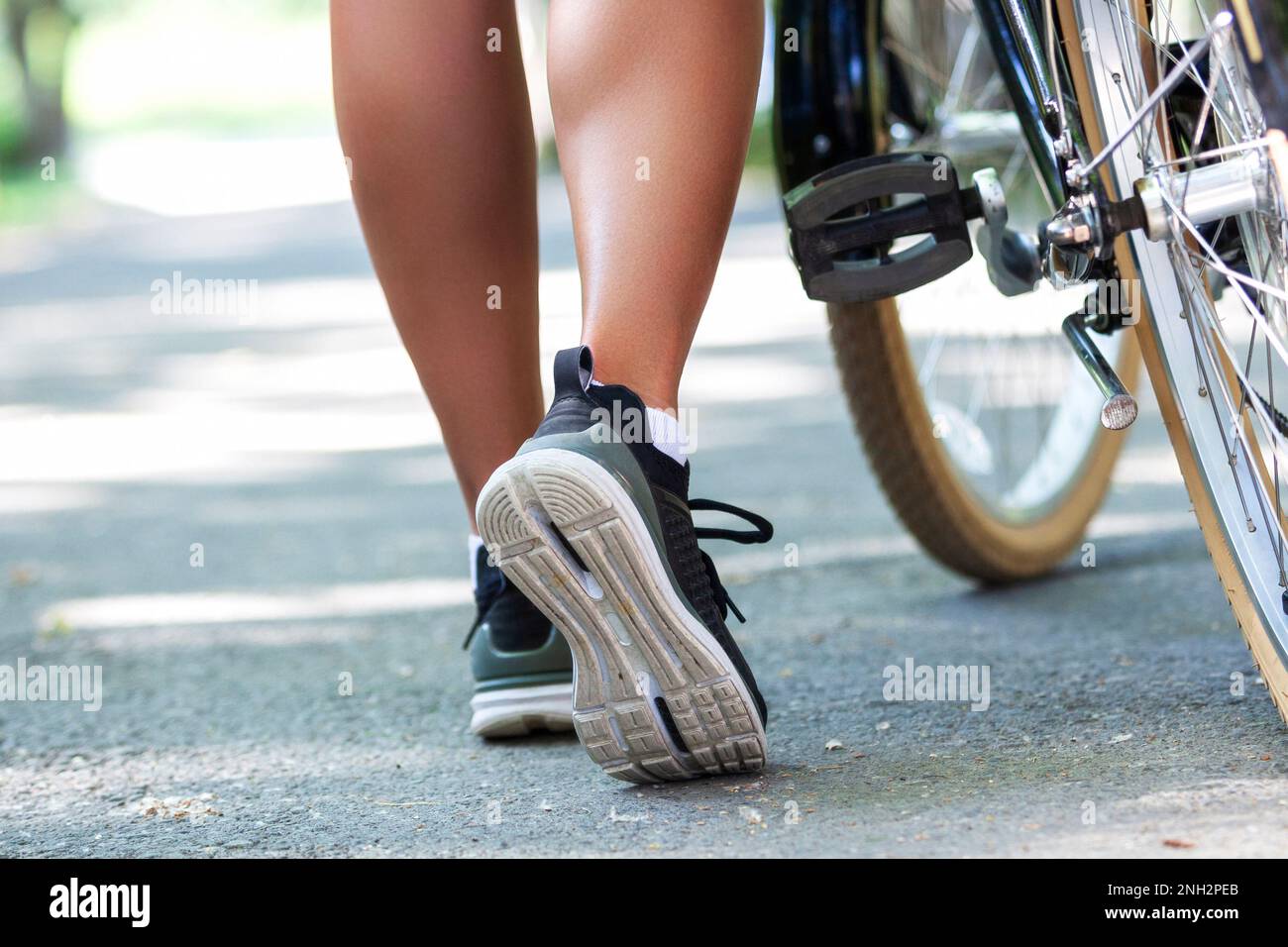 Legs of young fit woman riding bicycle in a city park Stock Photo - Alamy