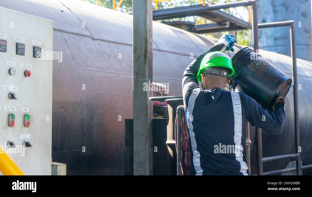 Oil plant worker dumping waste that will be recycled Stock Photo - Alamy