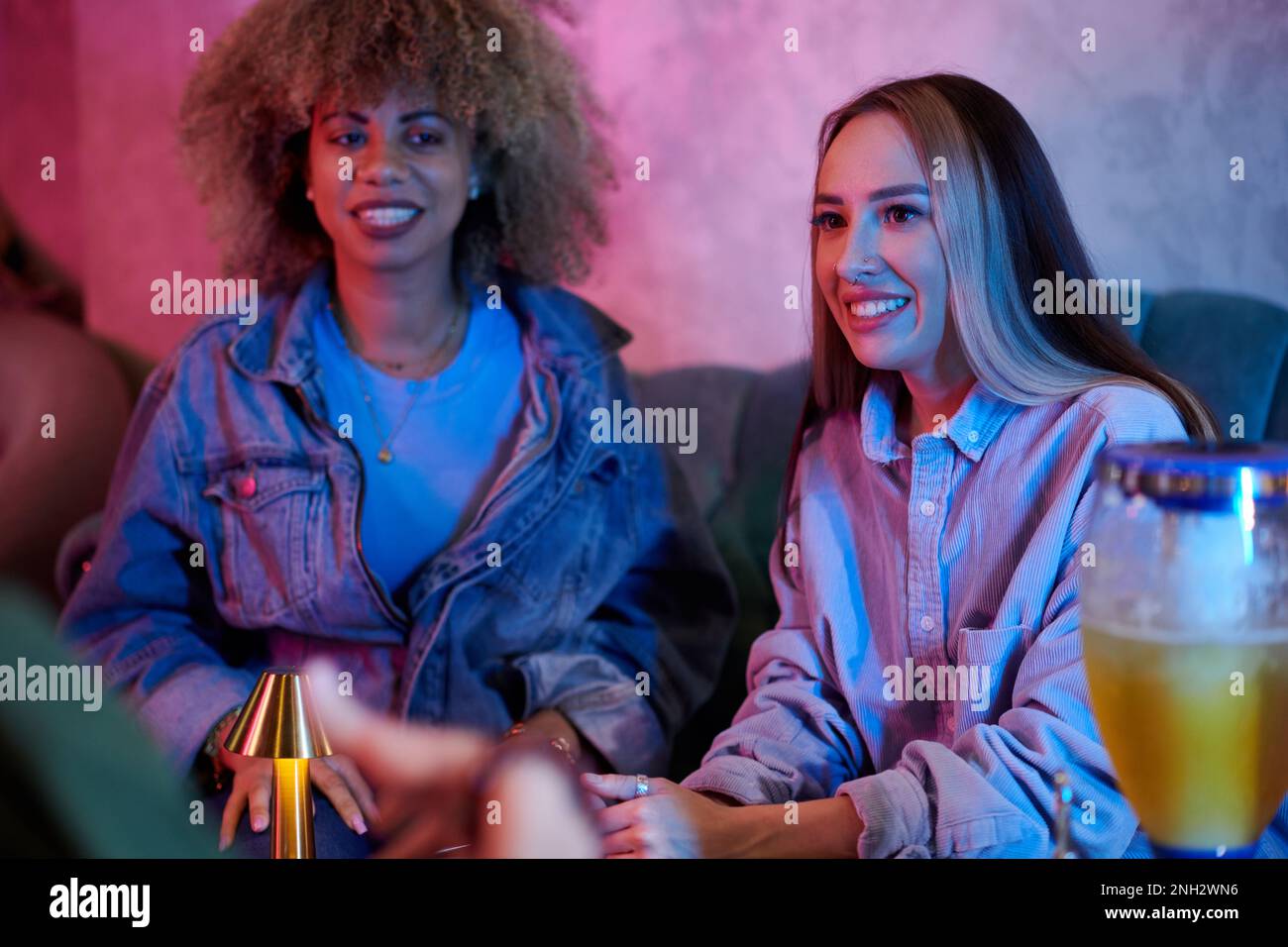 Cheerful young women hanging out with friends in pub Stock Photo - Alamy