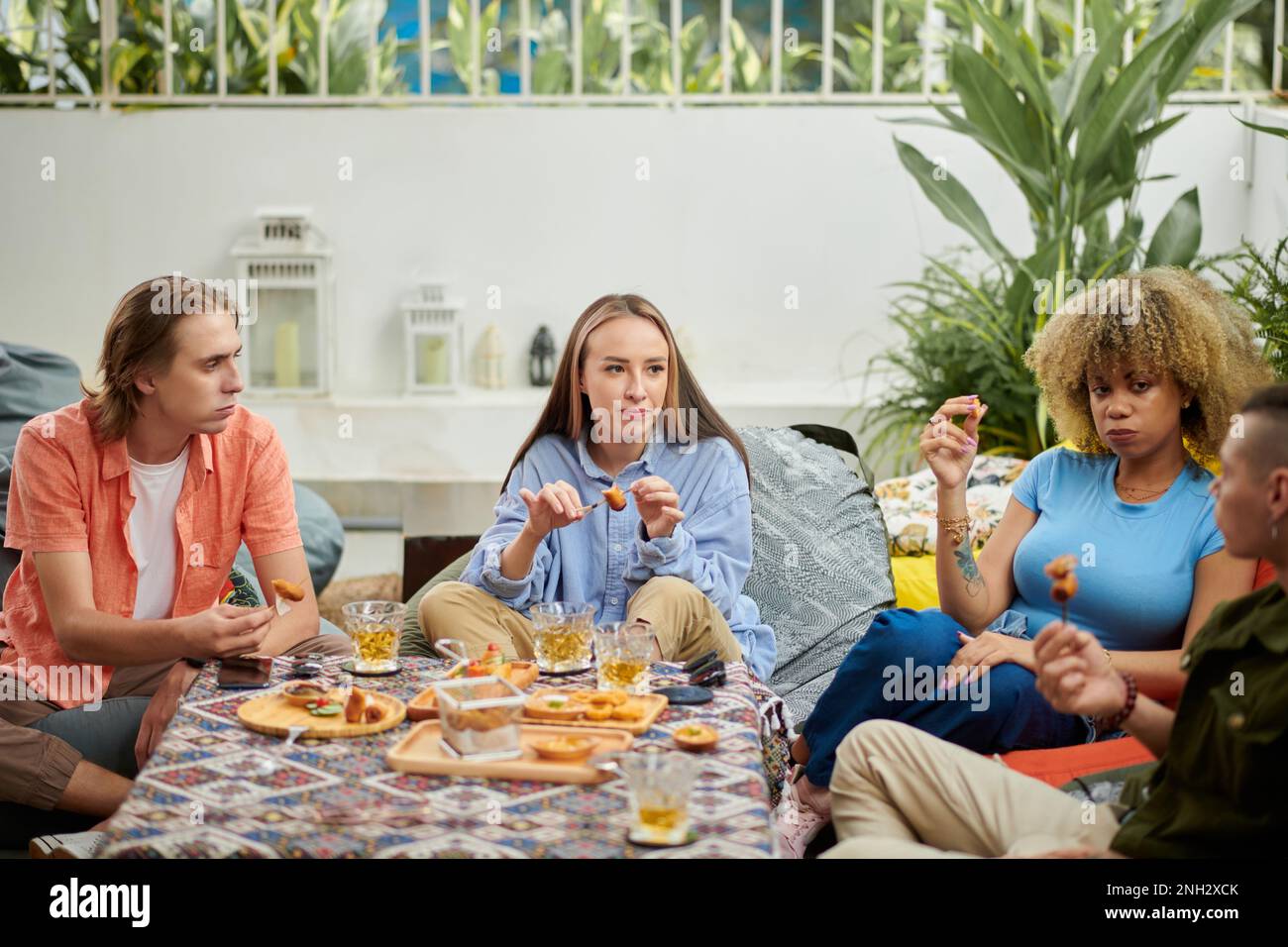 Group of young people eating snacks and drinking beer when hanging out ...
