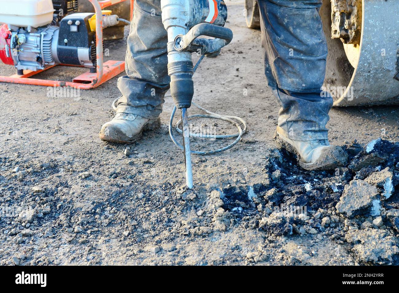 Builder breaking asphalt with electric breaker Stock Photo - Alamy