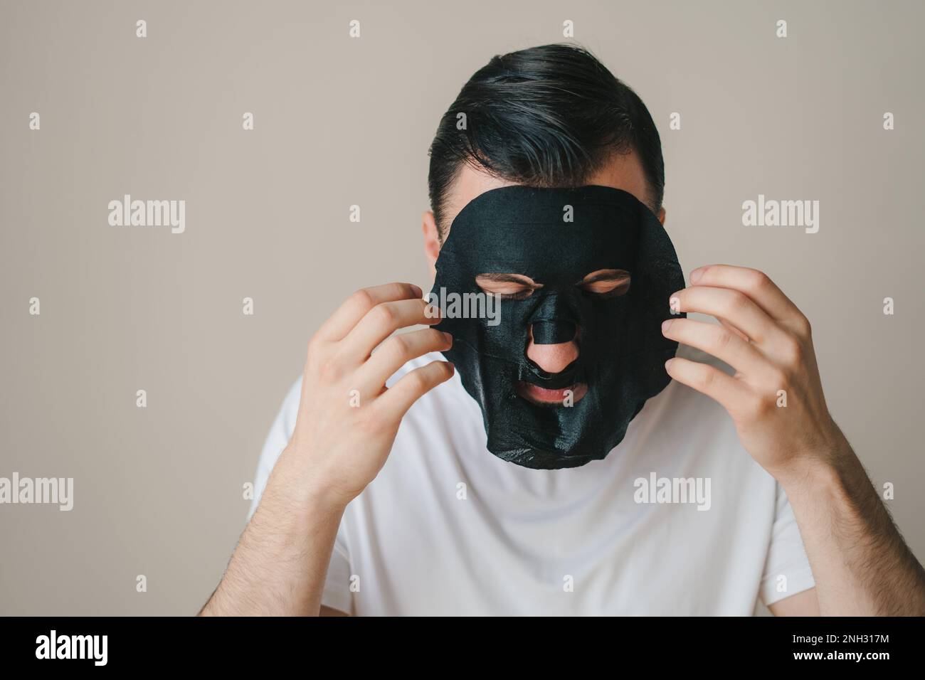 Close-up portrait of attractive handsome man applying skincare facial ...