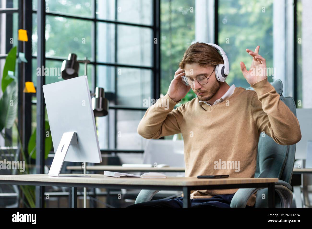 A young male programmer, freelancer sits in the office at the table ...