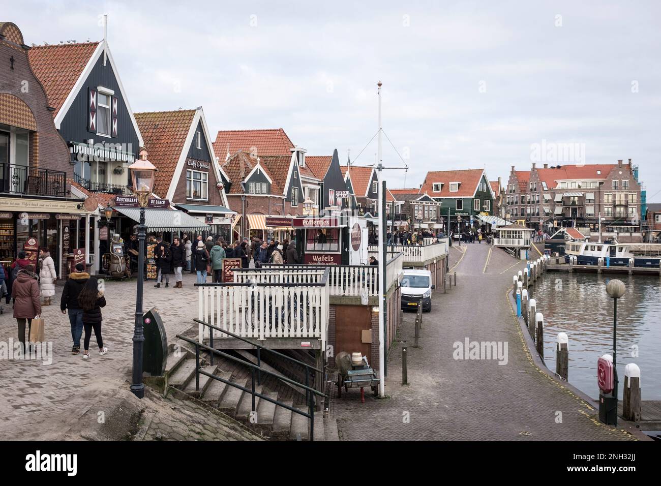 People walk along the waterfront promenade by the harbour in the winter ...